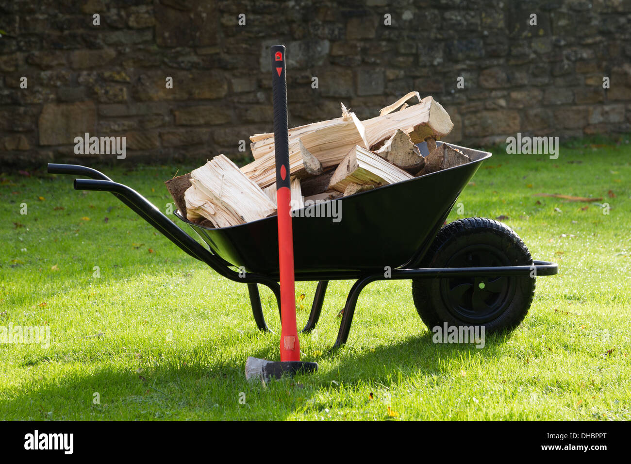 Wheelbarrow full of logs with log splitter Stock Photo - Alamy