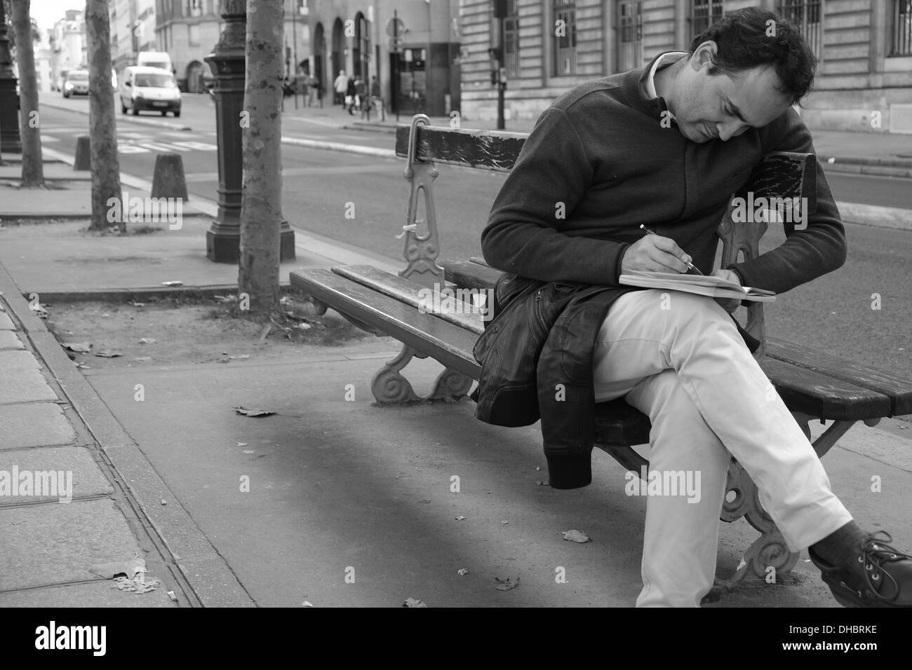 Man sitting on a bench writing Stock Photo - Alamy