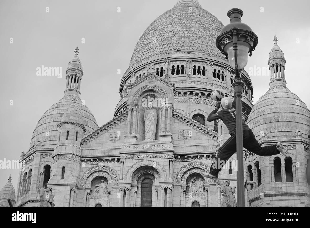 Boy climbing street light in front of the Sacré Coeur cathedral Stock ...
