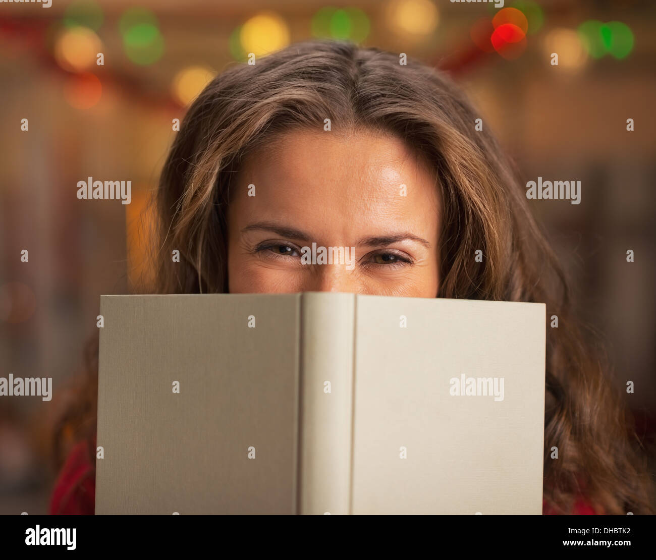 Happy young woman hiding behind book Stock Photo - Alamy