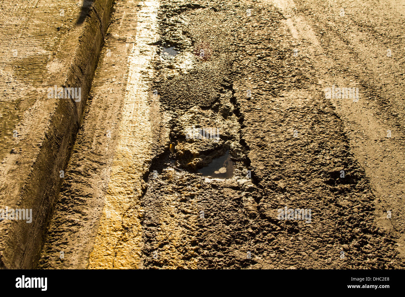 Black broken road surface with a yellow line Stock Photo - Alamy