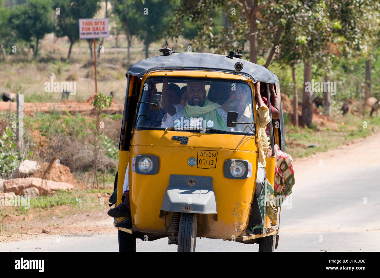 Orange yellow tuk-tuk, rickshaw, traveling with numerous passengers ...