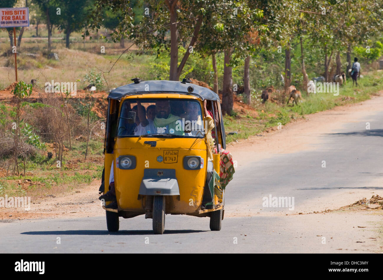 Orange yellow tuk-tuk, rickshaw, traveling with numerous passengers ...