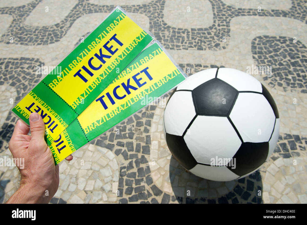 Hand holds two World Cup tickets above football soccer ball in Rio de ...