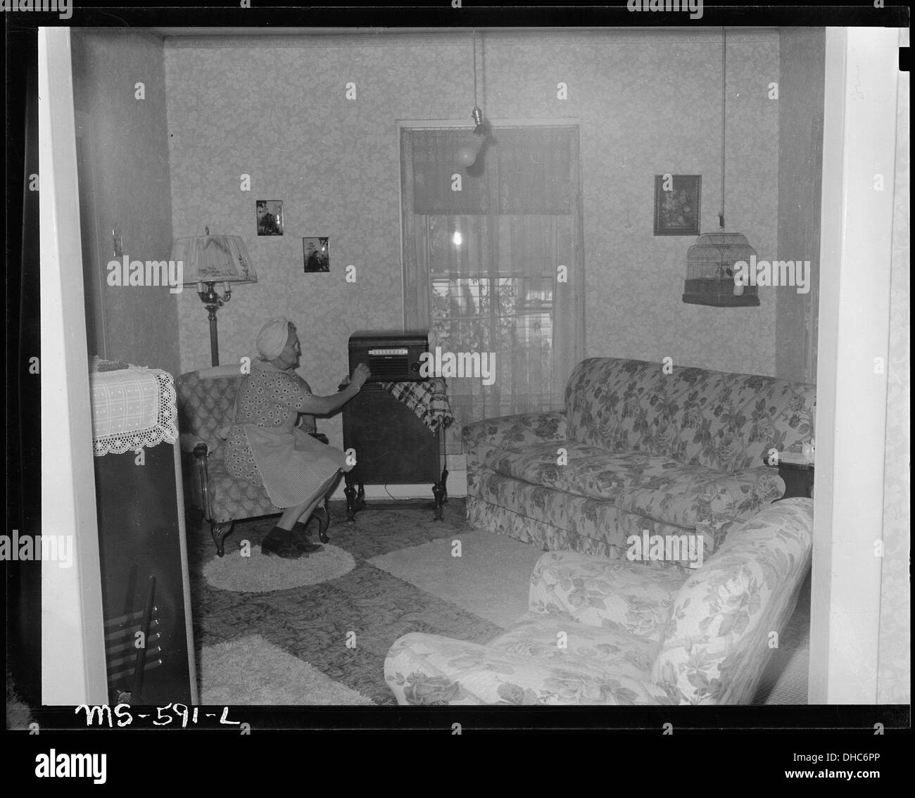 Mrs. Jessie Manchester, wife of a miner, is shown turning on a radio in ...