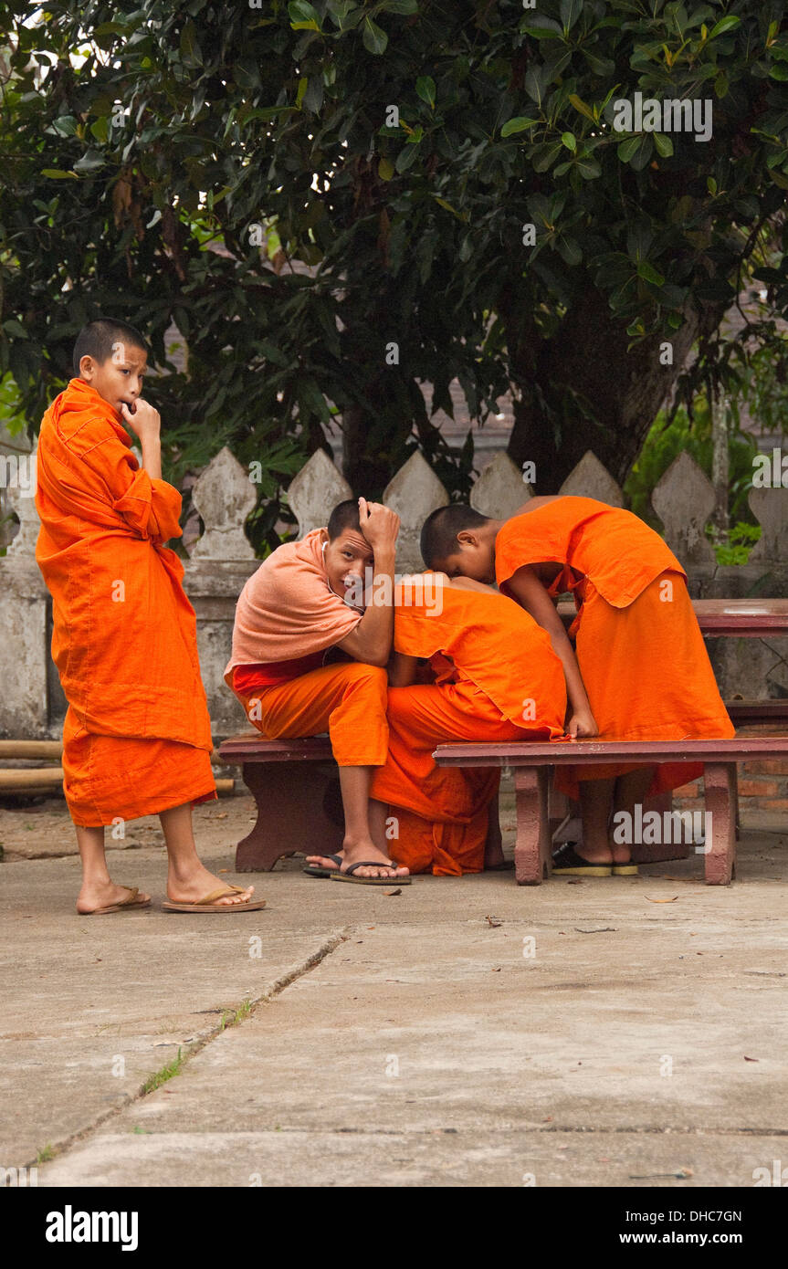 Vertical portrait of young Buddhist monks listening to music on an MP3 ...