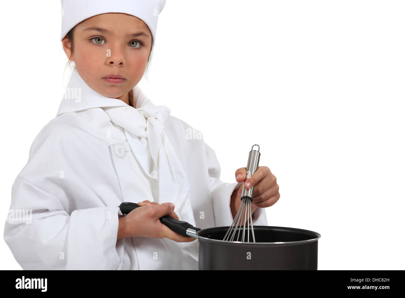 a little girl dressed in chief cook uniform is cooking Stock Photo - Alamy