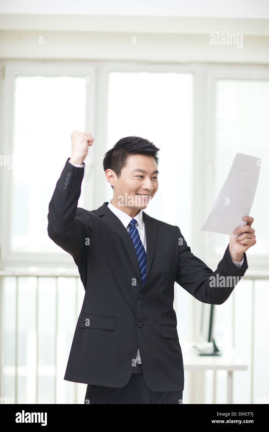 Portrait of young businessman standing,looking documents and holding ...