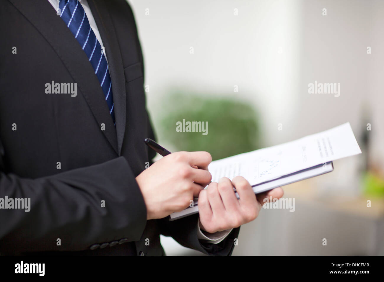 Portrait of young businessman looking and signing documents Stock Photo ...