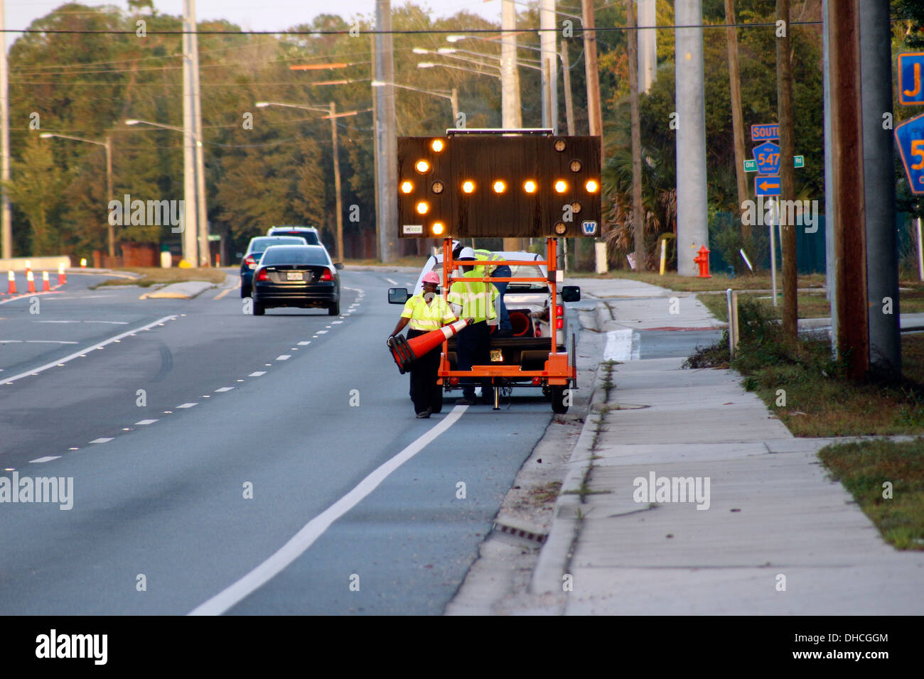 Road workers setting up for a lane closure on a busy highway in Stock ...