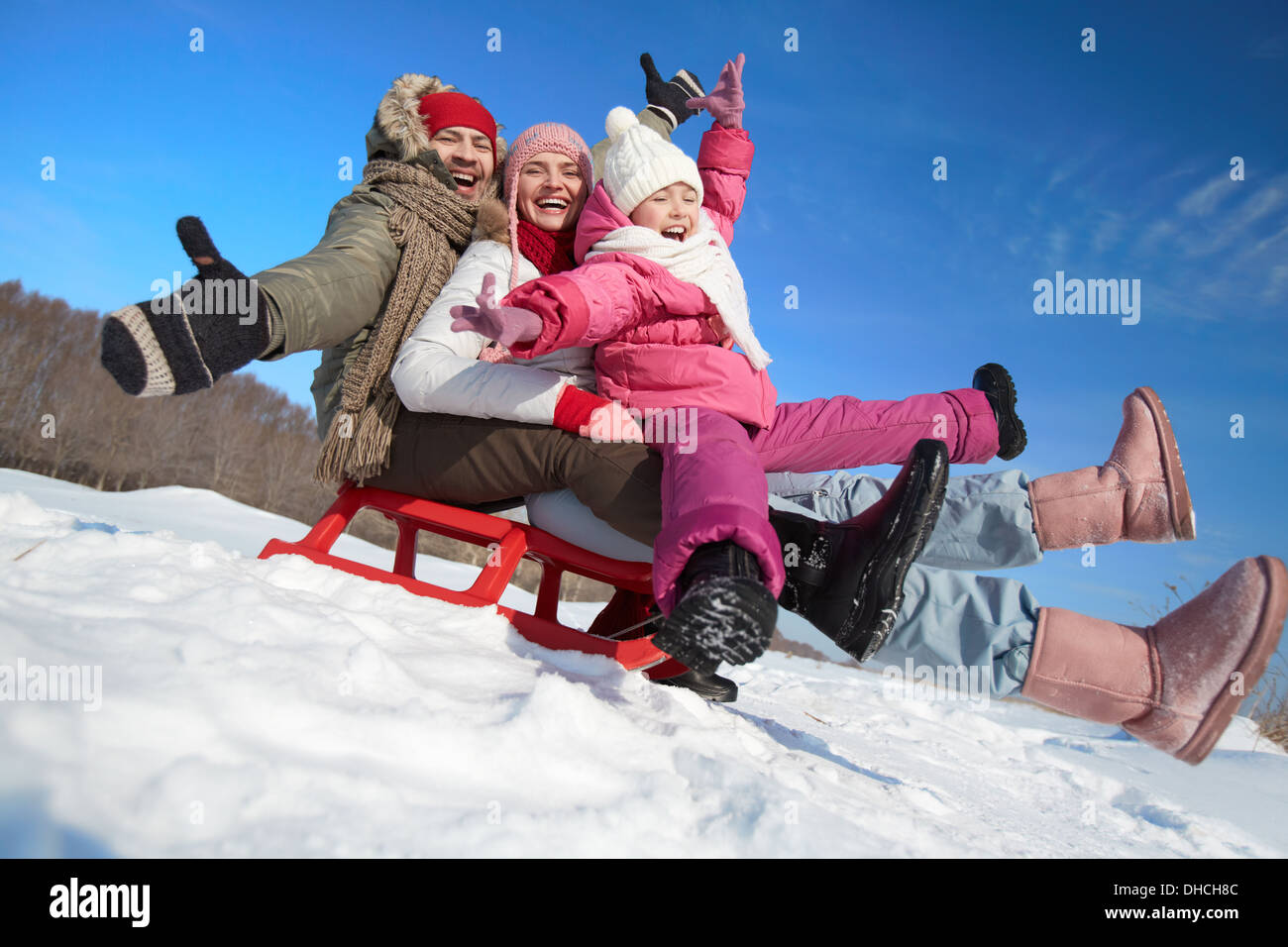 Happy couple and their daughter sitting on sledge Stock Photo - Alamy