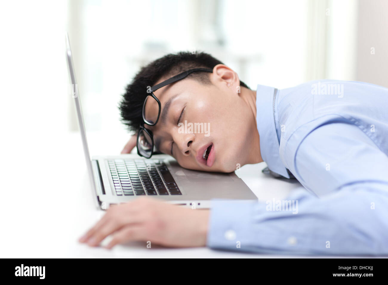 Portrait of young businessman sleeping on laptop by desk,close-up Stock ...