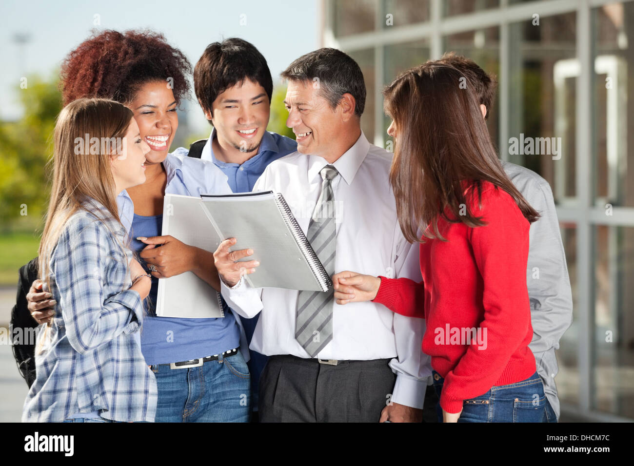 Students And Teacher With Book Standing On University Campus Stock ...