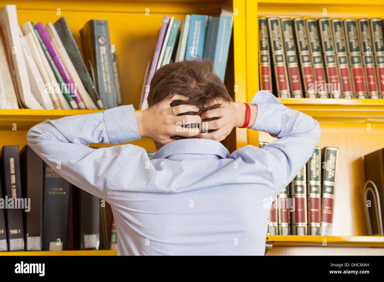 Student Pulling Hair Against Bookshelf In University Library Stock ...