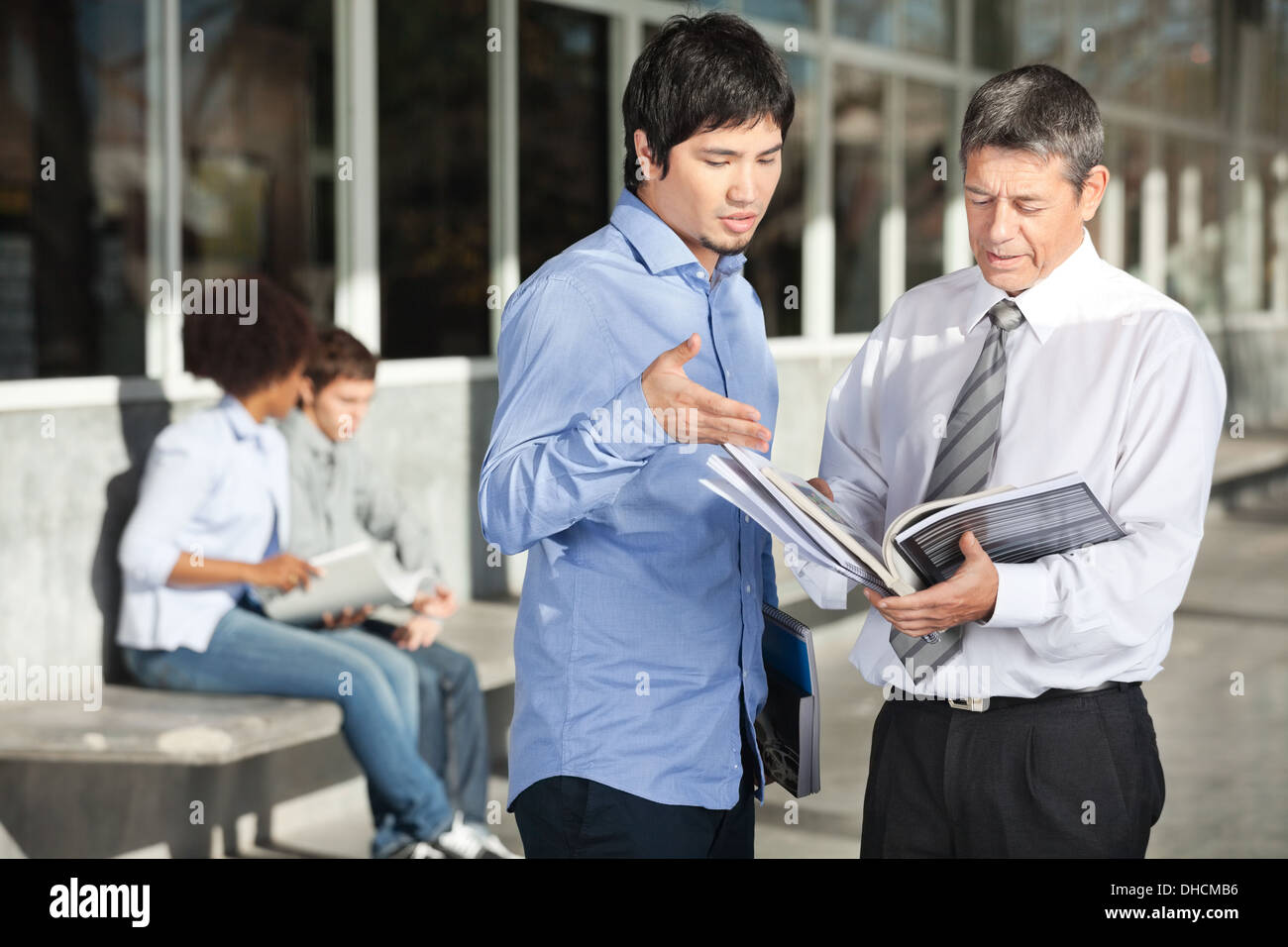 Teacher Holding Books While Discussing With Student On Campus Stock ...