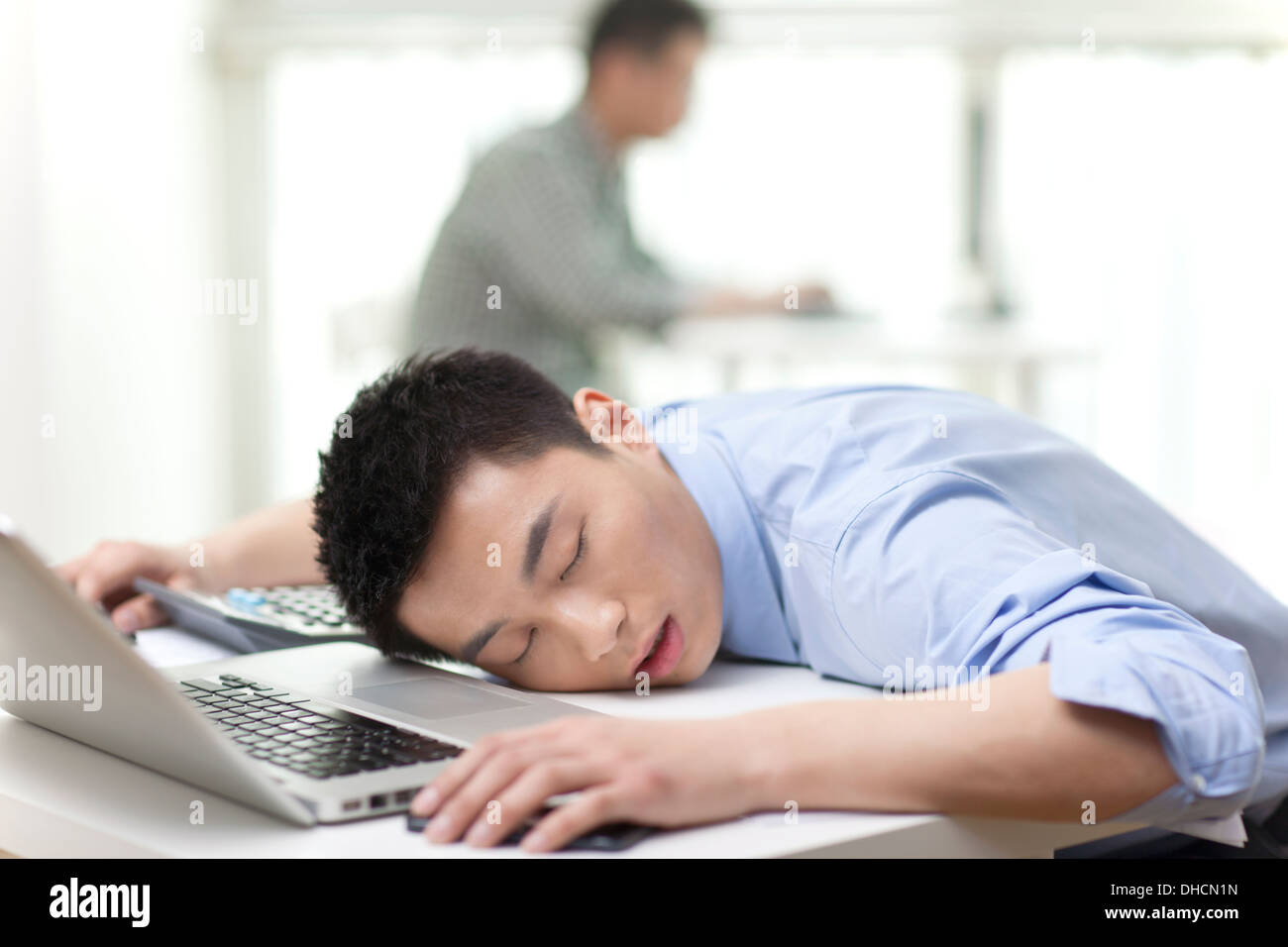 Portrait of young businessman sleeping on laptop by desk Stock Photo ...