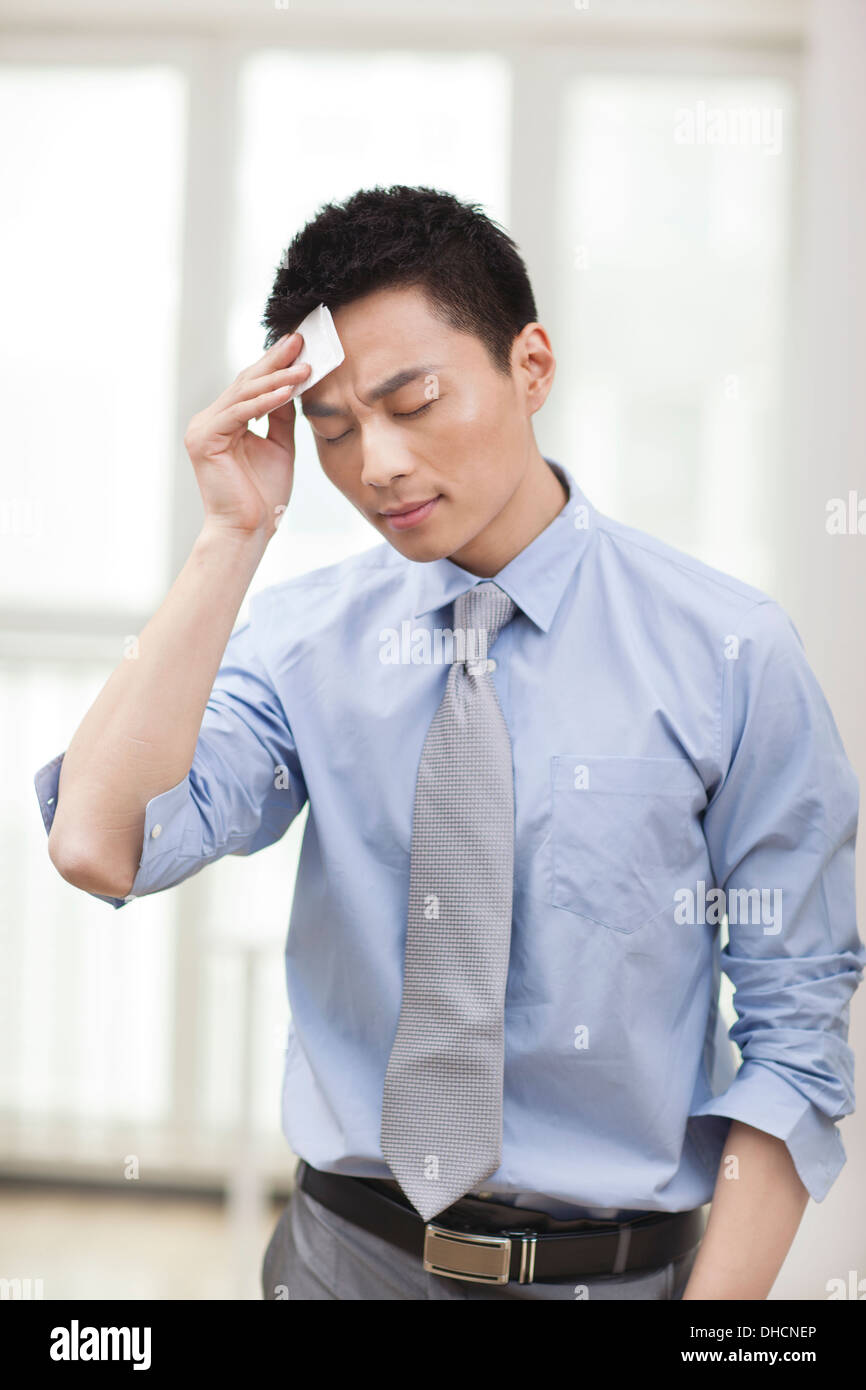 Portrait of young businessman wiping forehead Stock Photo - Alamy