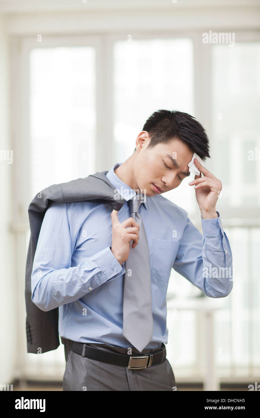 Portrait of young businessman wiping forehead Stock Photo - Alamy