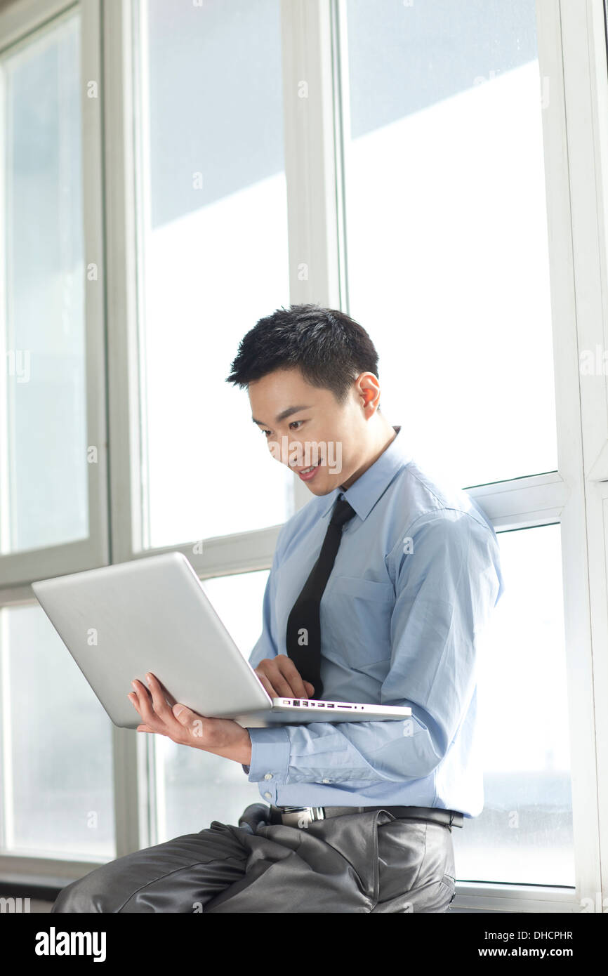 Portrait of young businessman holding laptop in corridor Stock Photo ...