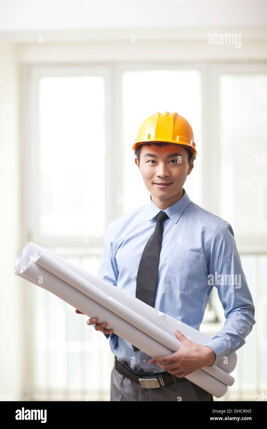 Portrait of young engineer holding blueprint in office Stock Photo - Alamy