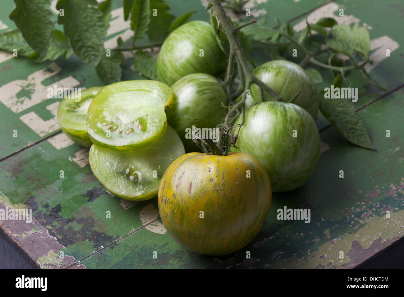 Sliced and whole green zebra tomatoes (Solanum lycopersicum), studio ...