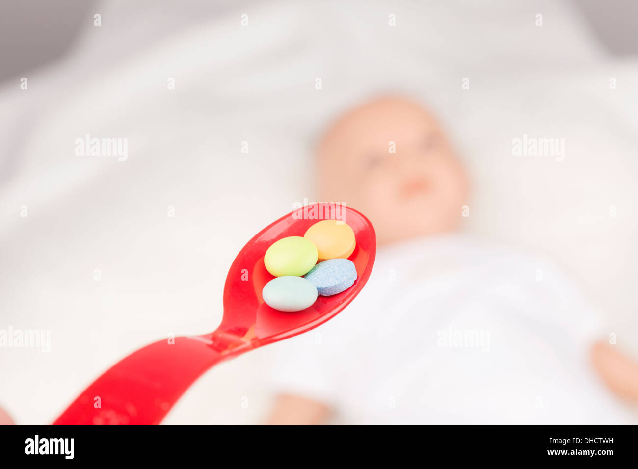 Spoon with tablets and baby doll in background Stock Photo - Alamy