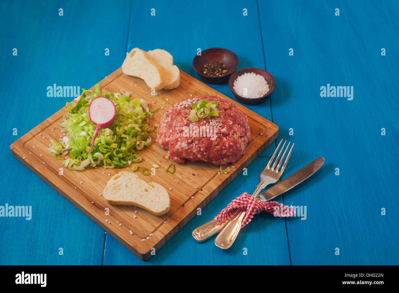 Raw minced meat with spring onions and bread on chopping board, studio ...