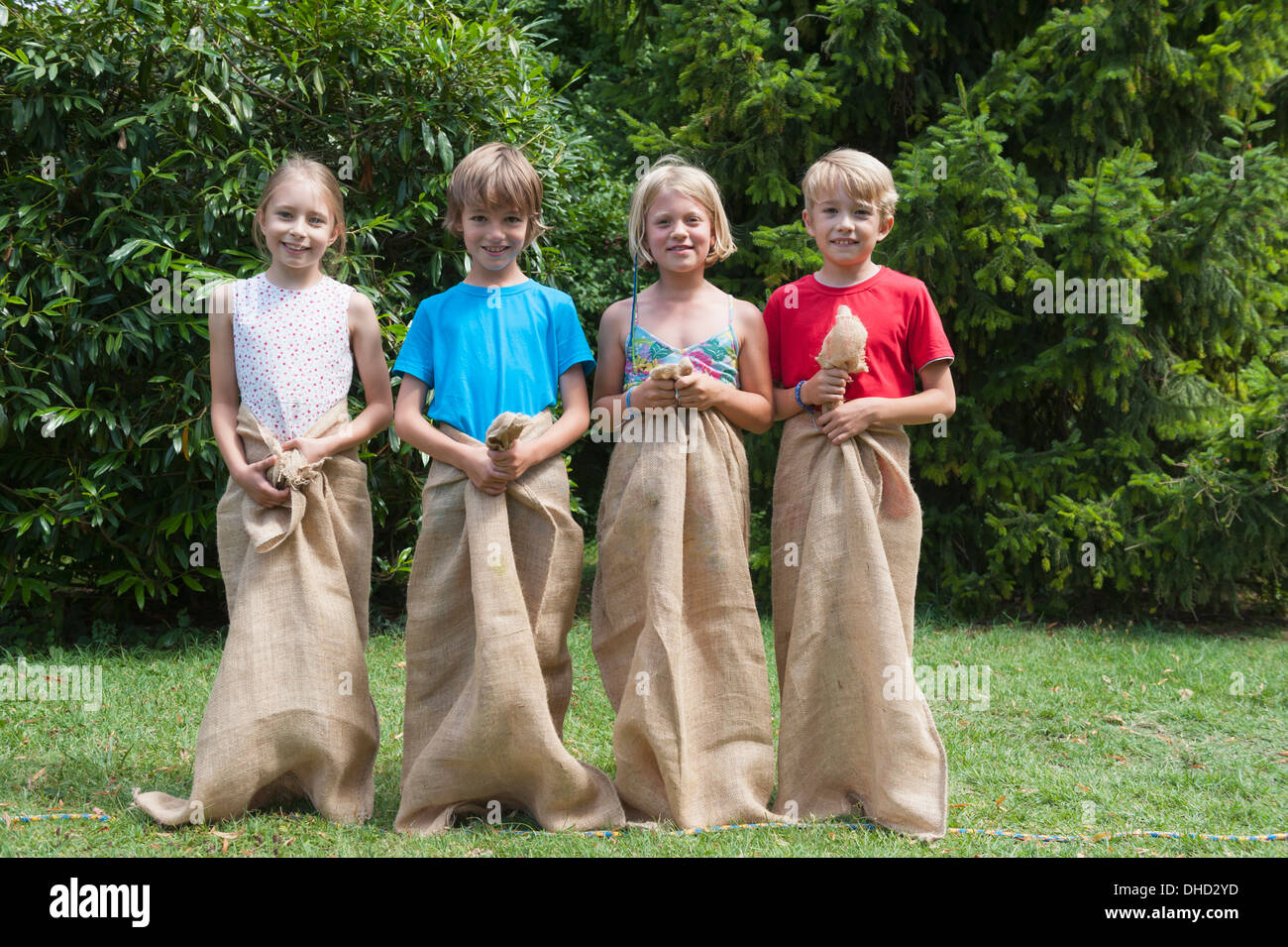 Four children standing in sacks side by side Stock Photo - Alamy