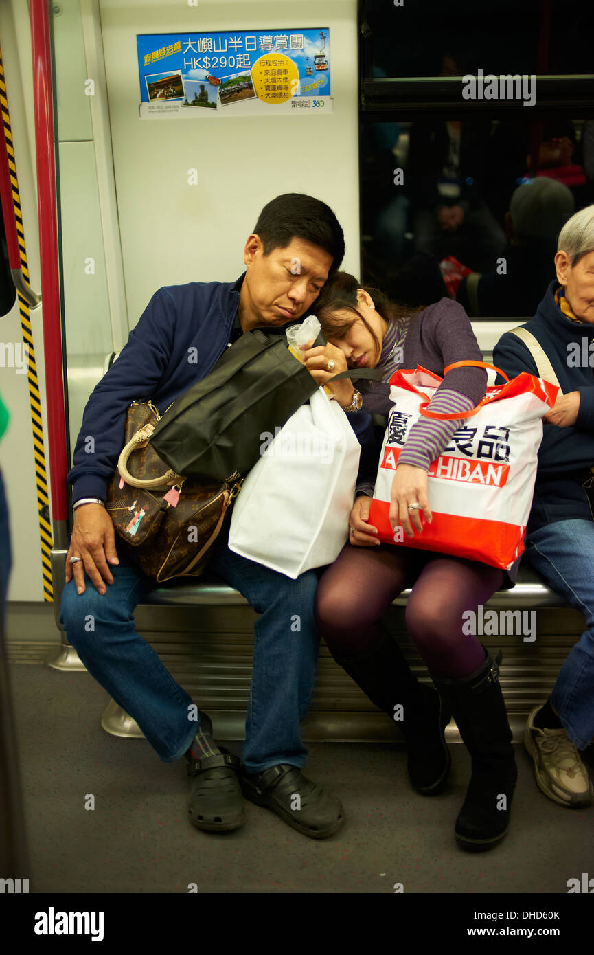 2 people asleep on a commuter train in Hong Kong with their shopping ...