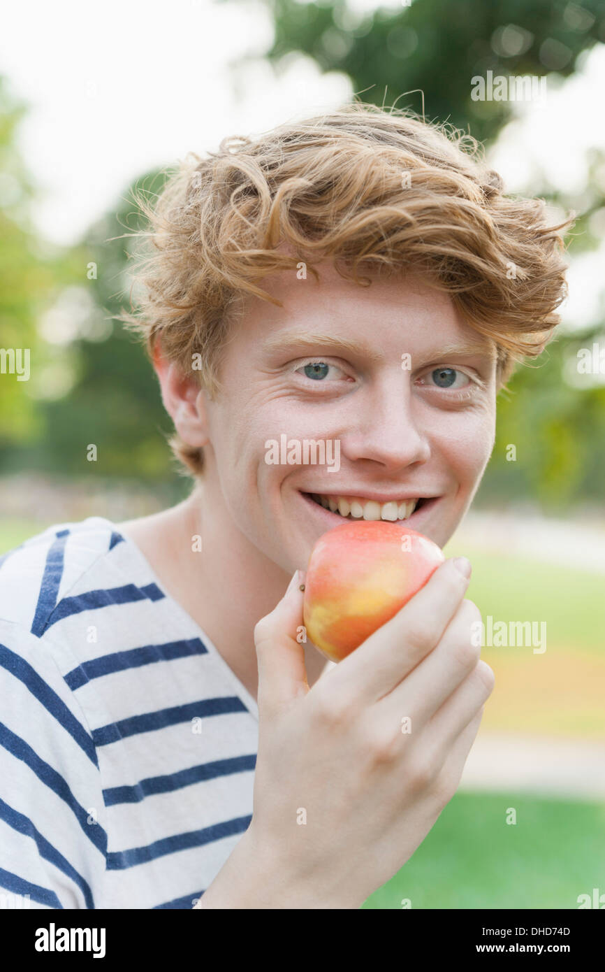 Young man eating an apple outdoors Stock Photo - Alamy
