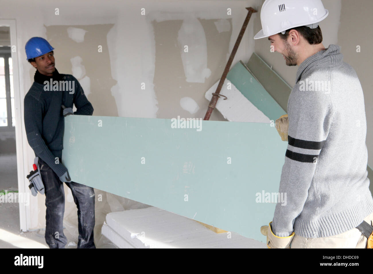 Two builders carrying plasterboard Stock Photo - Alamy