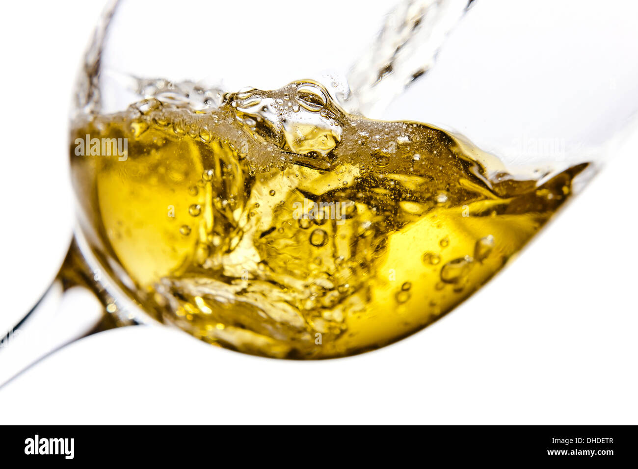 White wine being poured into a wineglass, isolated on white background ...