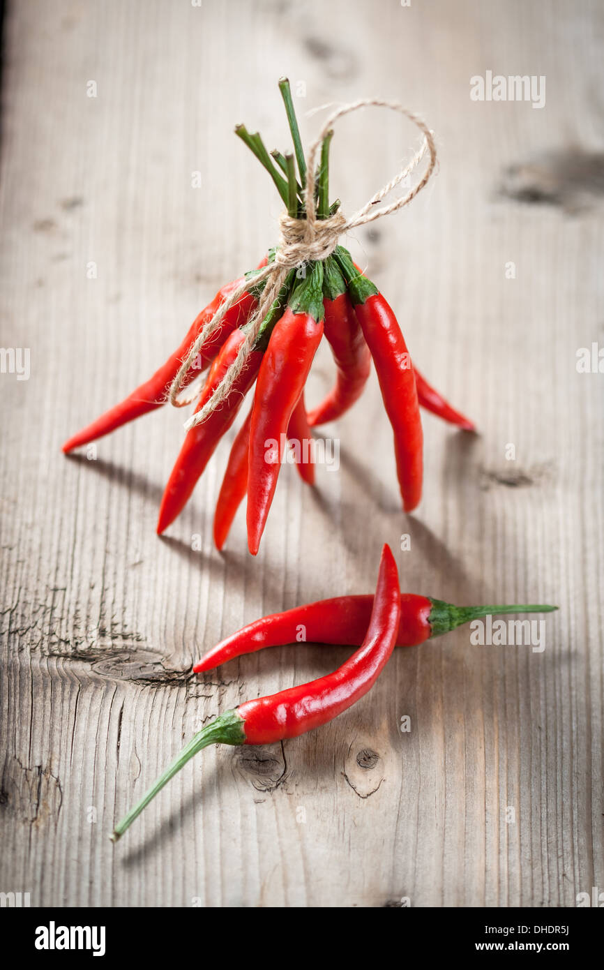 Red hot chili peppers tied with ropen wooden background Stock Photo - Alamy