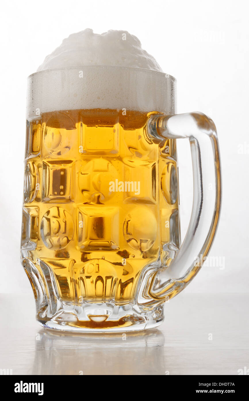 a beer glass mug with overflowing foam on a reflecting surface Stock ...