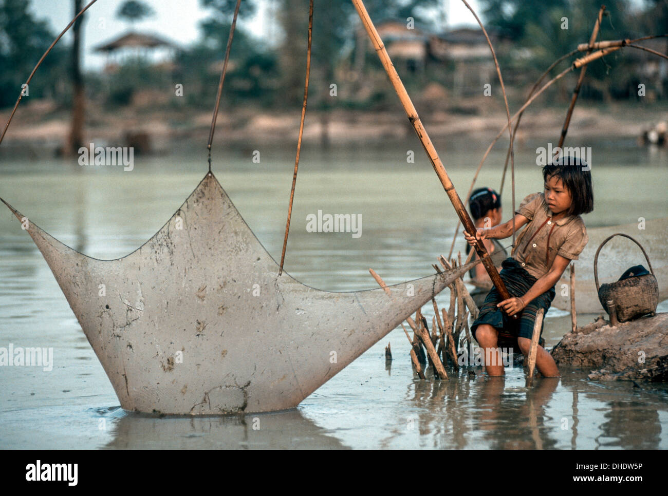 Village children stand in the water use bamboo fishing rods & suspended ...