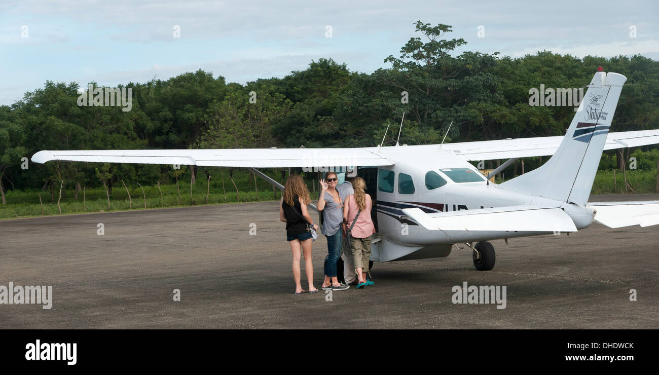 A Woman Waves Goodbye As She And Two Daughters Board A Plane On A ...