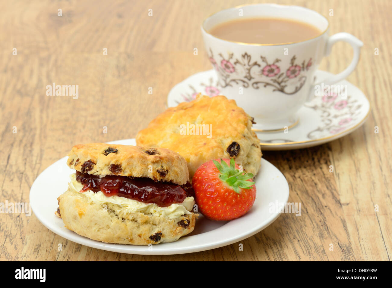 Two cream tea scones with clotted cream and strawberry jam with a cup ...