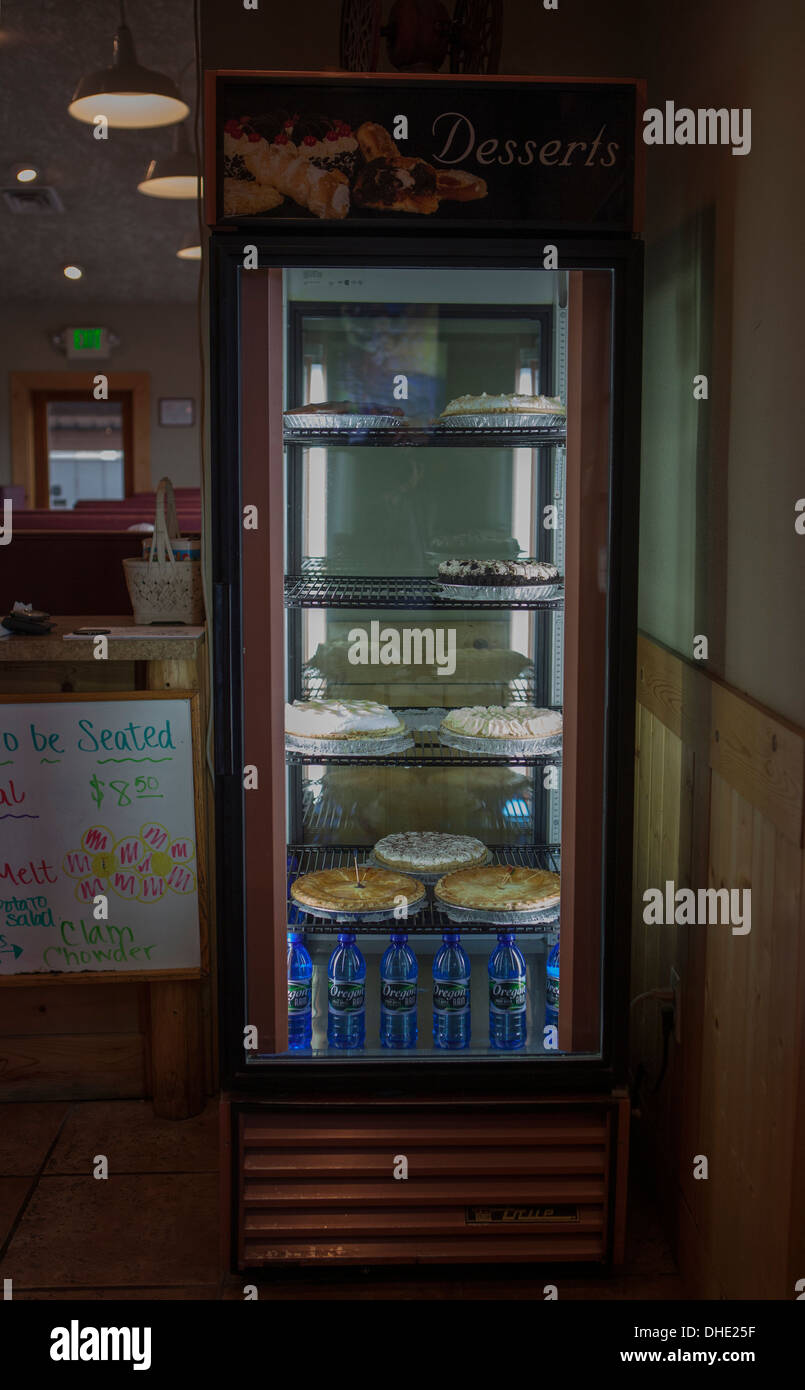 vertical dessert case in diner displaying pies, cakes, and bottled ...