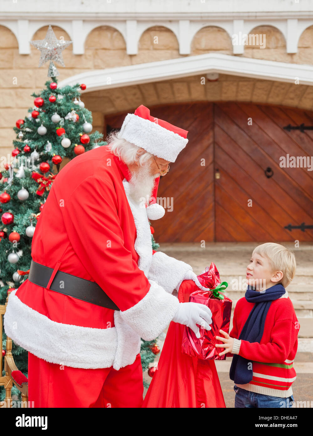 Boy Looking At Santa Claus While Taking Gift From Him Stock Photo - Alamy