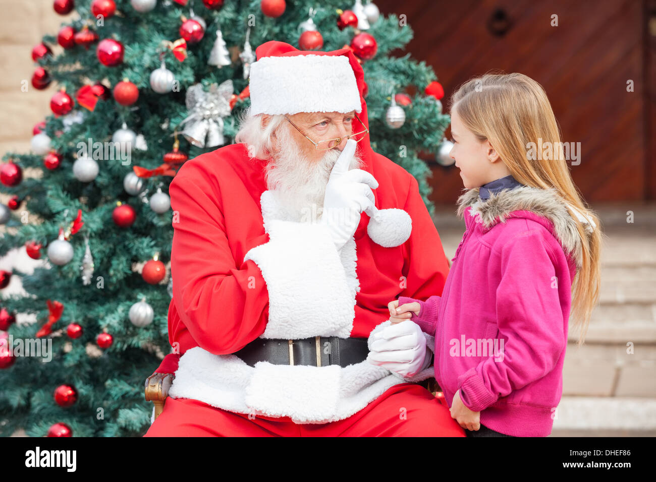 Girl Looking At Santa Claus Gesturing Finger On Lips Stock Photo - Alamy