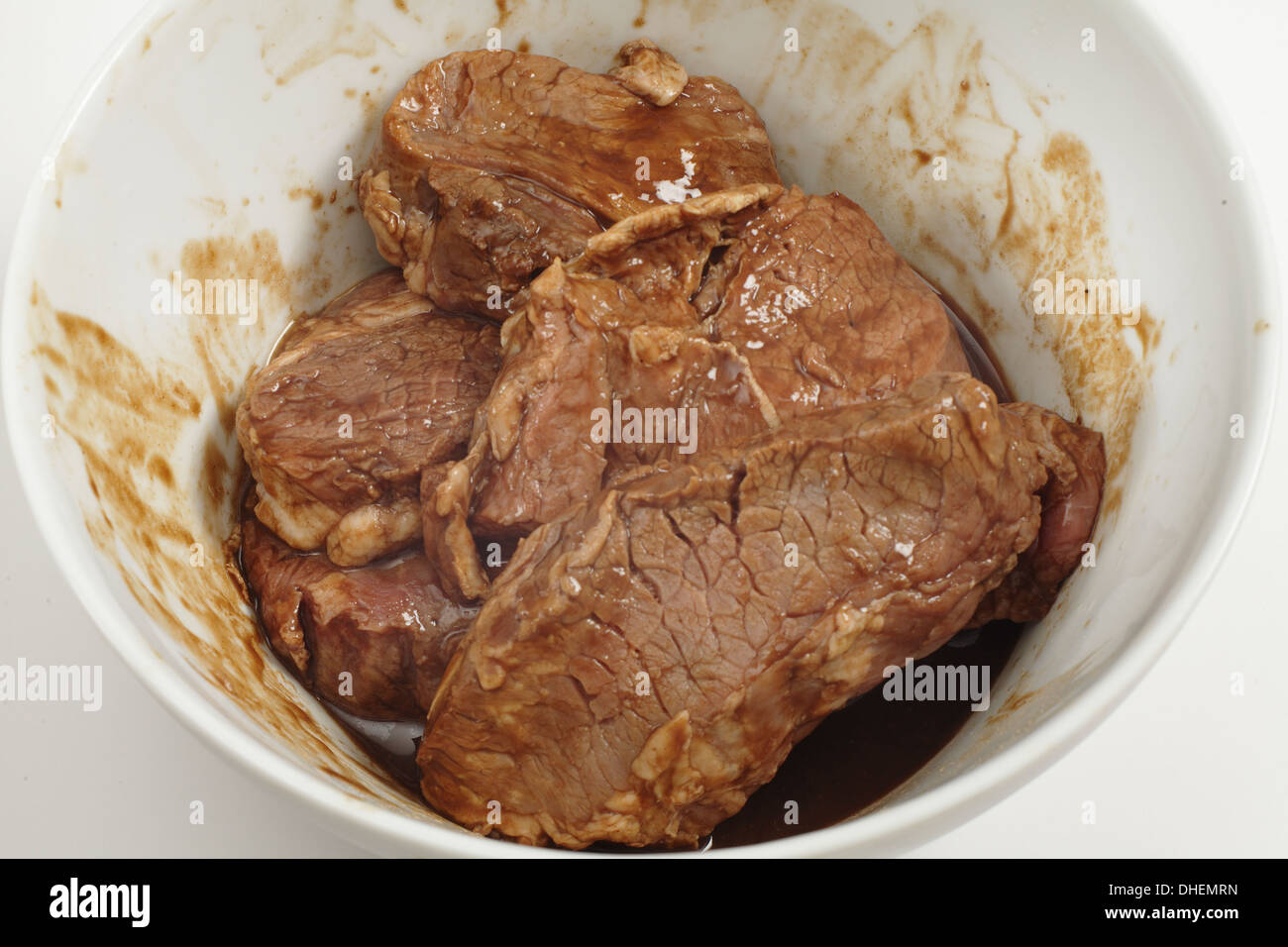 Lumps of beef steak being marinaded in a bowl ready for barbecuing ...