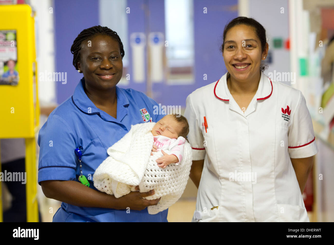 A midwife holds a new born baby with a student midwife looking on UK ...