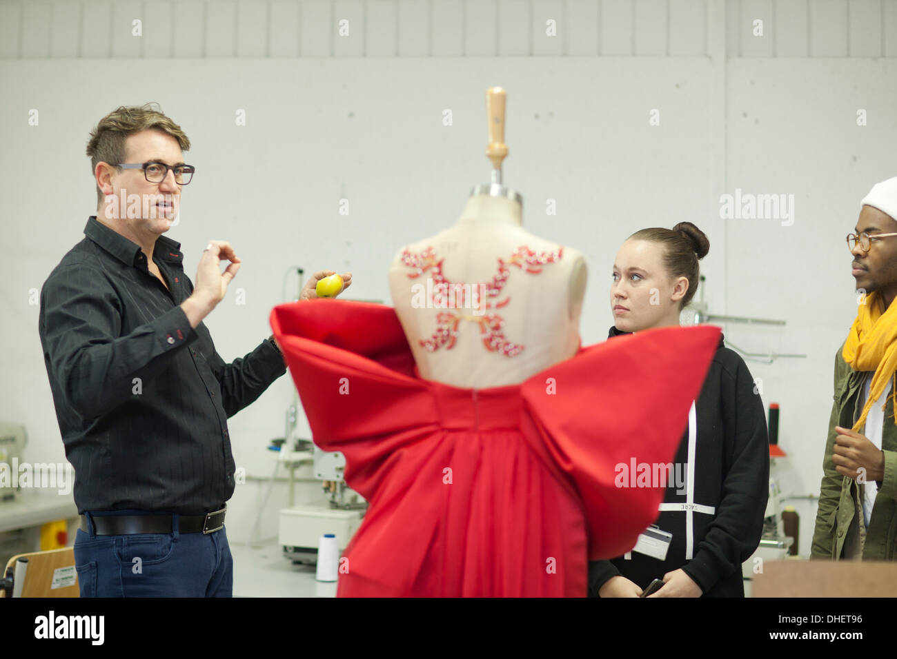 Fashion design teacher assessing students work Stock Photo - Alamy