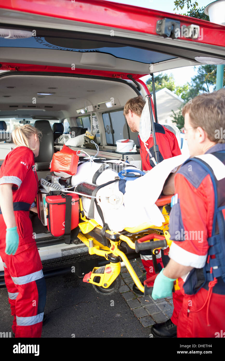 Paramedics lifting woman on stretcher into ambulance Stock Photo - Alamy