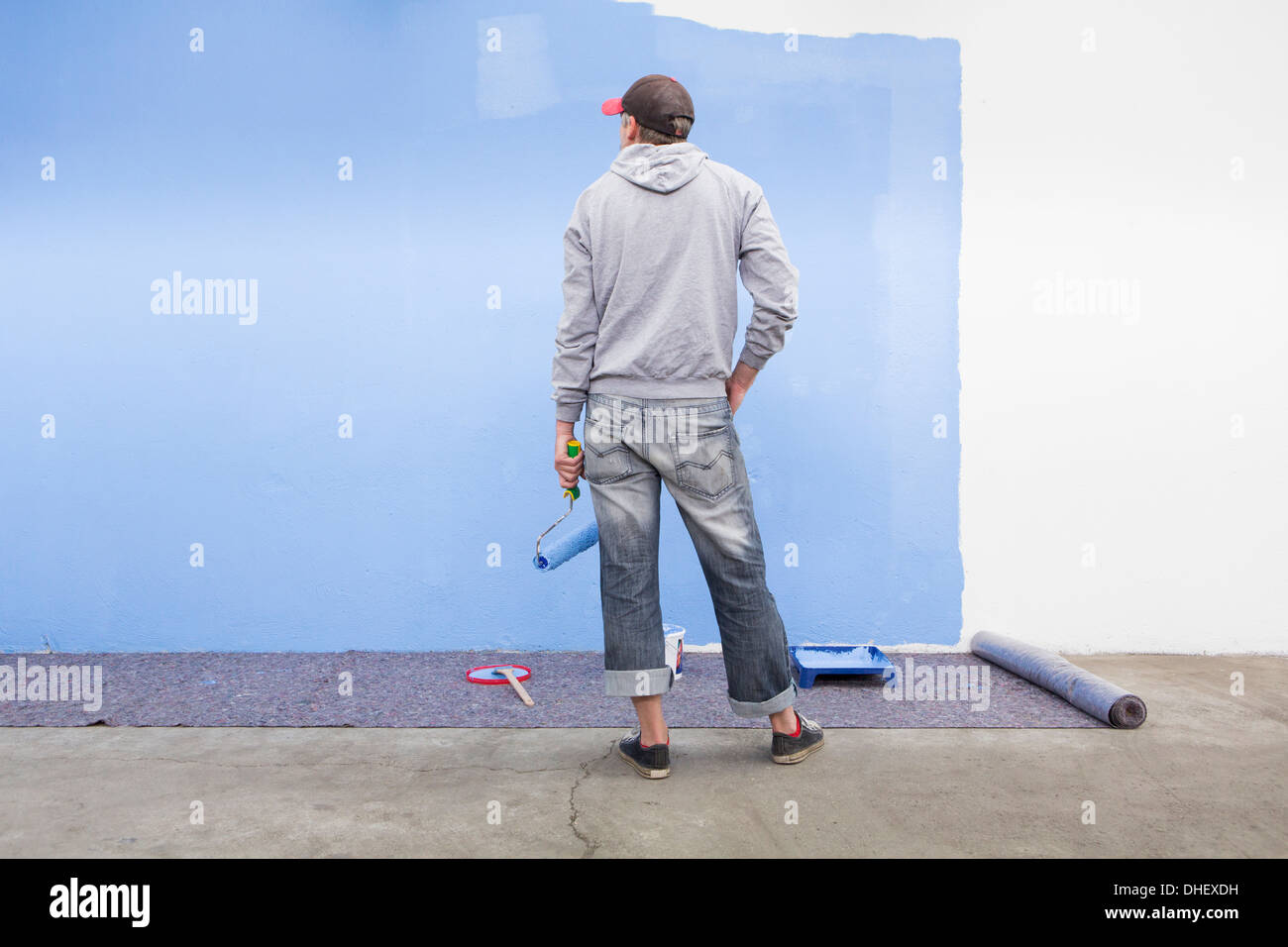 Rear view of man painting wall blue Stock Photo - Alamy