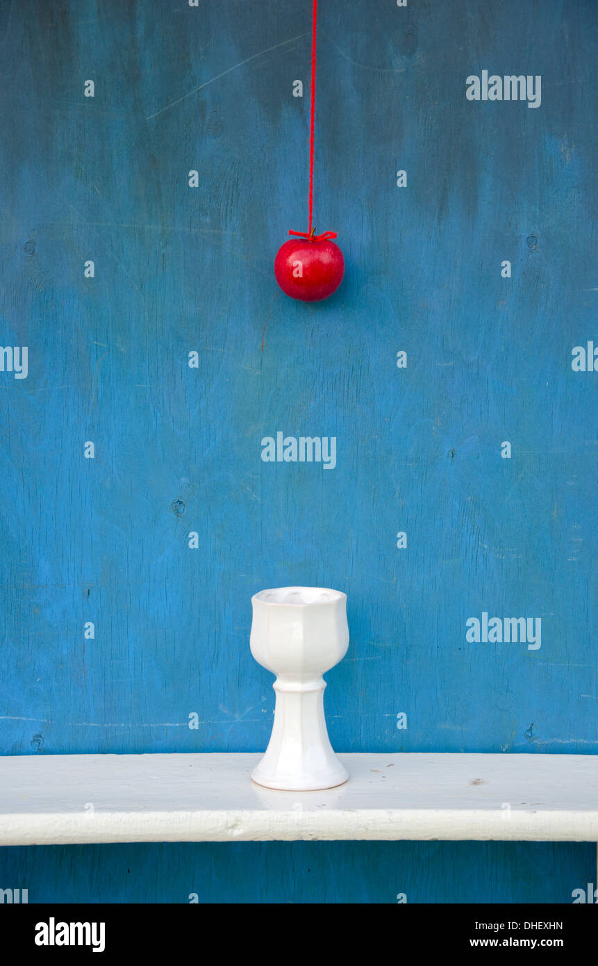 hanging red apple on string and empty white vase on shelf Stock Photo ...
