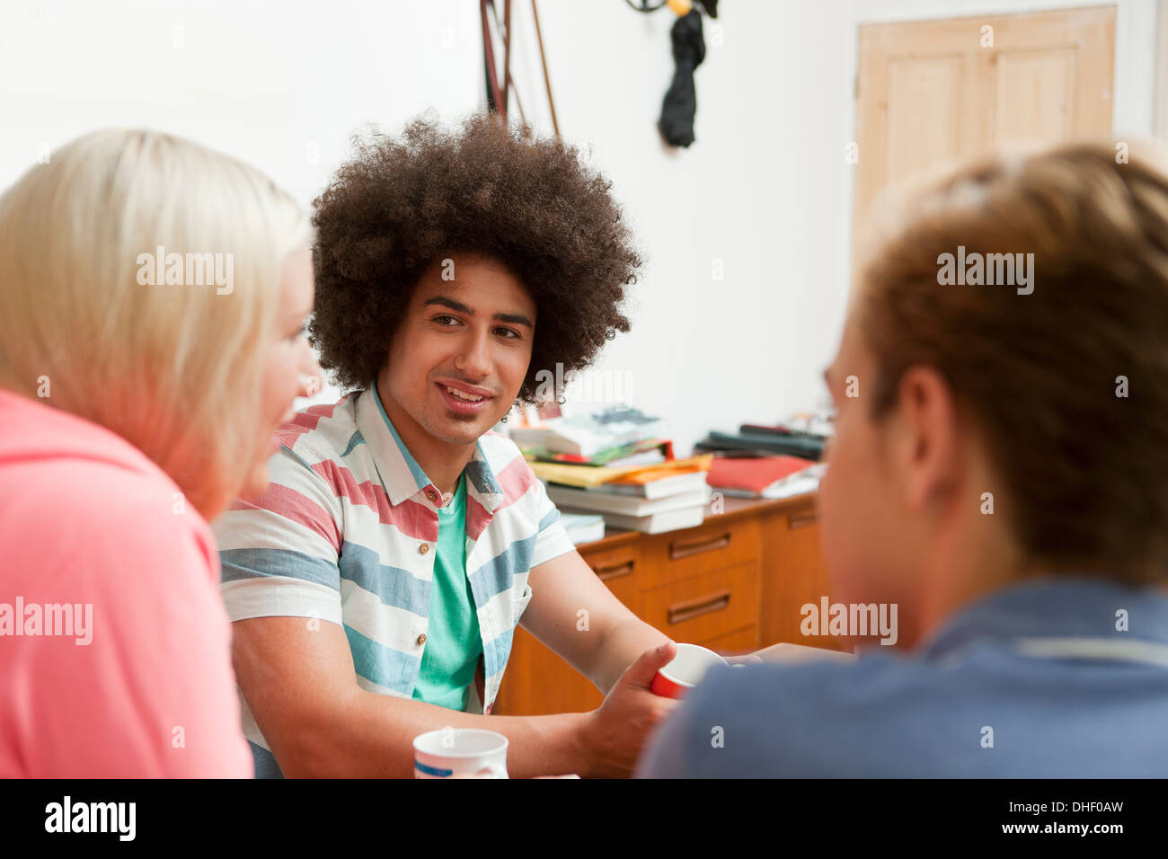 Group of young friends sitting around kitchen table Stock Photo - Alamy