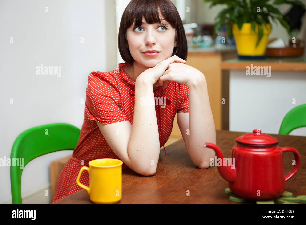 Portrait of young woman sitting at kitchen table Stock Photo - Alamy