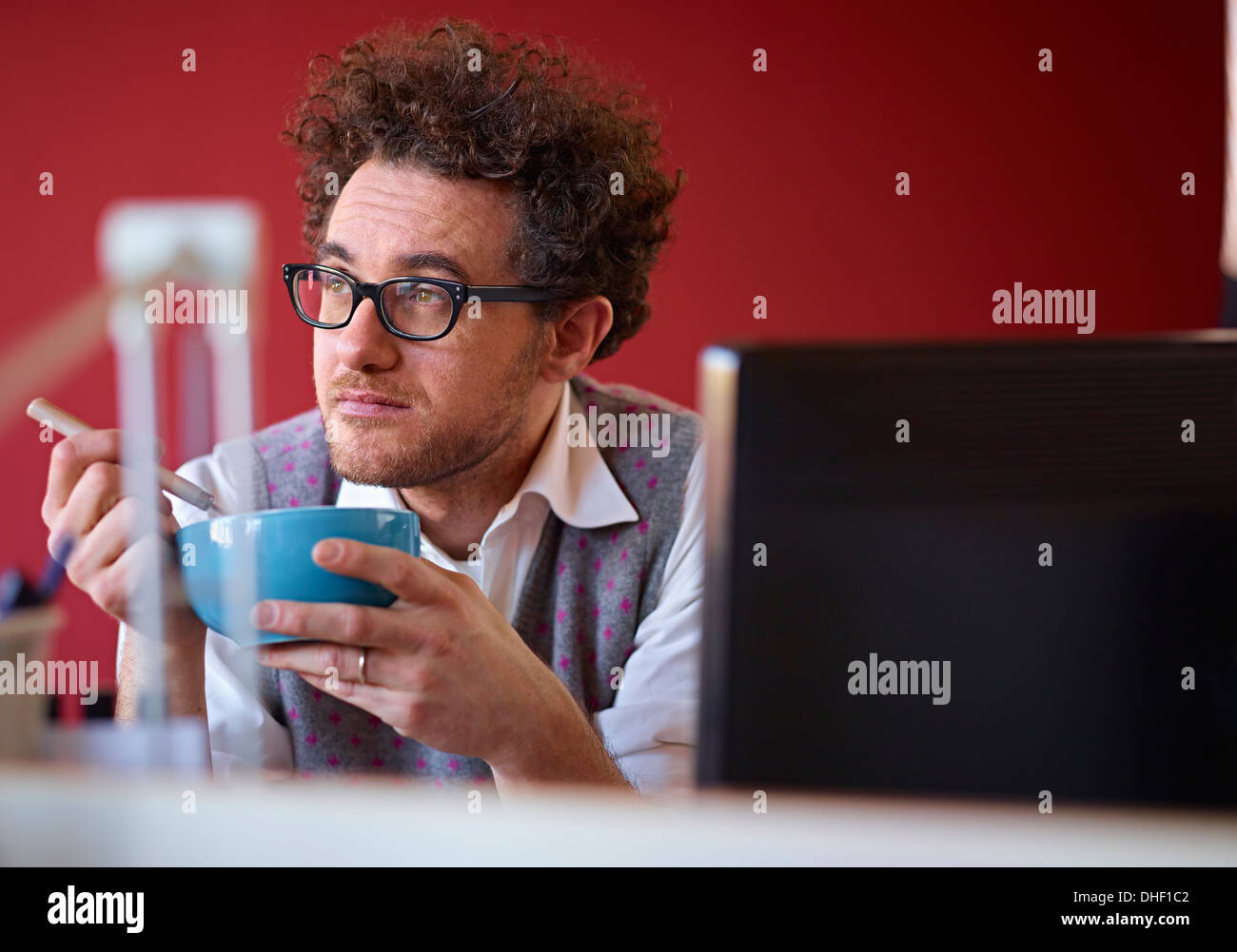 Office worker eating breakfast cereal at desk Stock Photo - Alamy