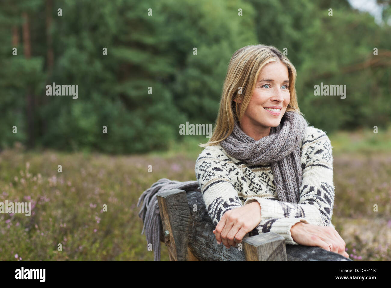 Mid adult woman wearing sweater on bench Stock Photo - Alamy